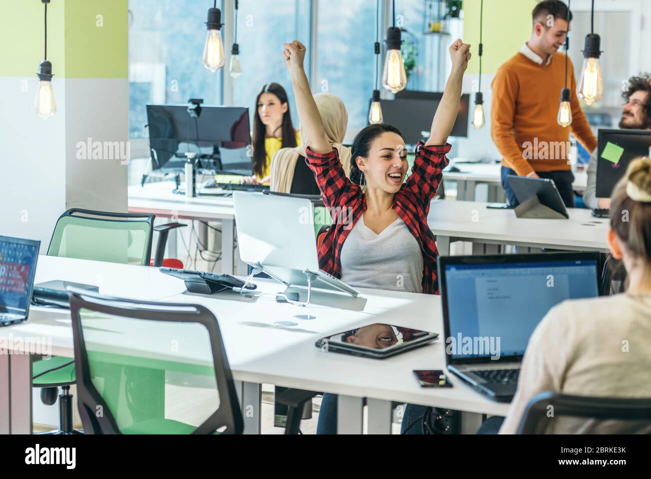 Happy employee cheering while lifting her hands high in the air while ...