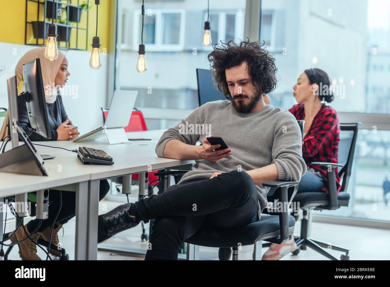 Bearded employee guy with afro haircut talking on his phone while being ...