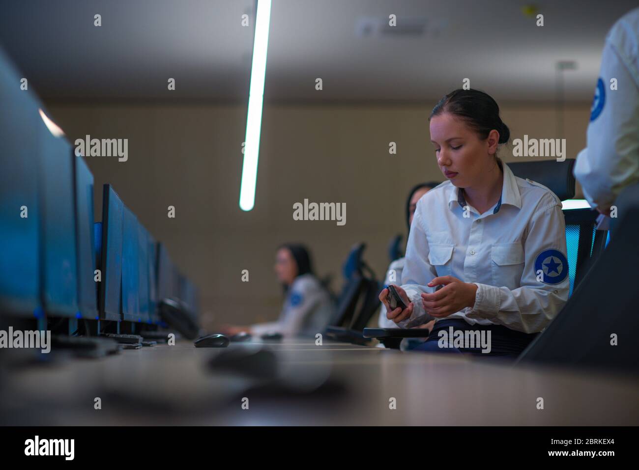 Female security guard sitting and monitoring modern CCTV cameras in a ...