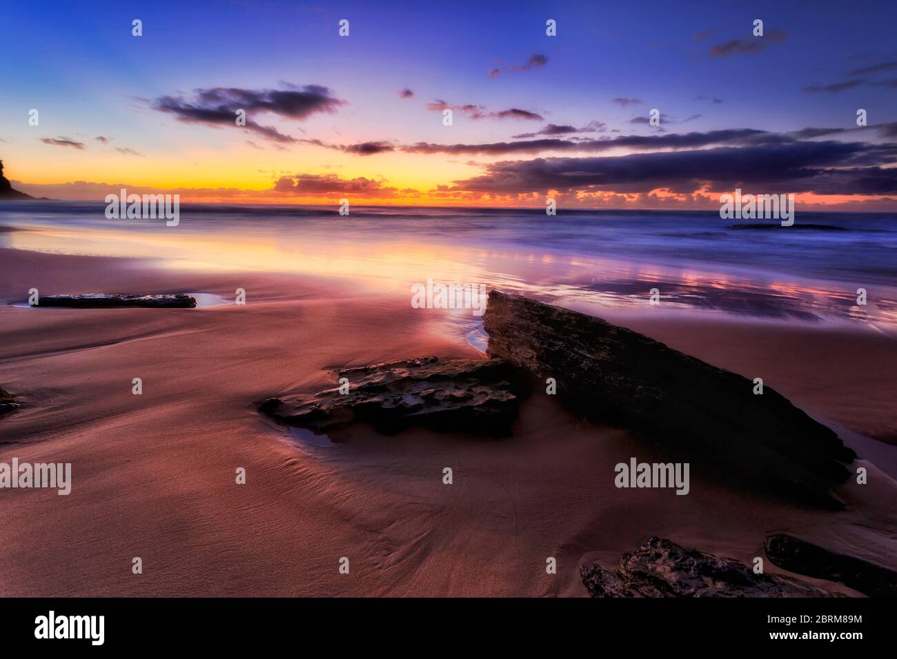 Dark sandstone rocks on sandy beach in Sydney on Pacific coast at ...