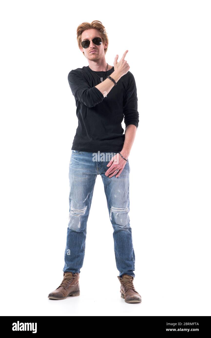 Stylish ginger young man in jeans pointing finger up above shoulder ...