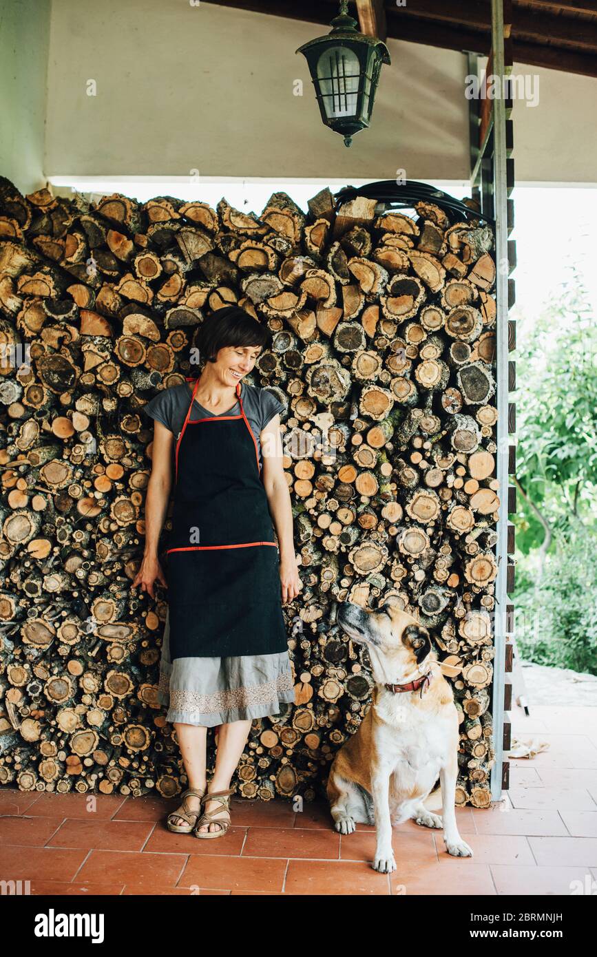 Professional female woodworker and dog at the pile of logs Stock Photo ...