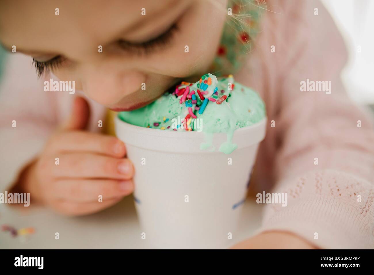 Girl eating ice cream with sprinkles Stock Photo - Alamy