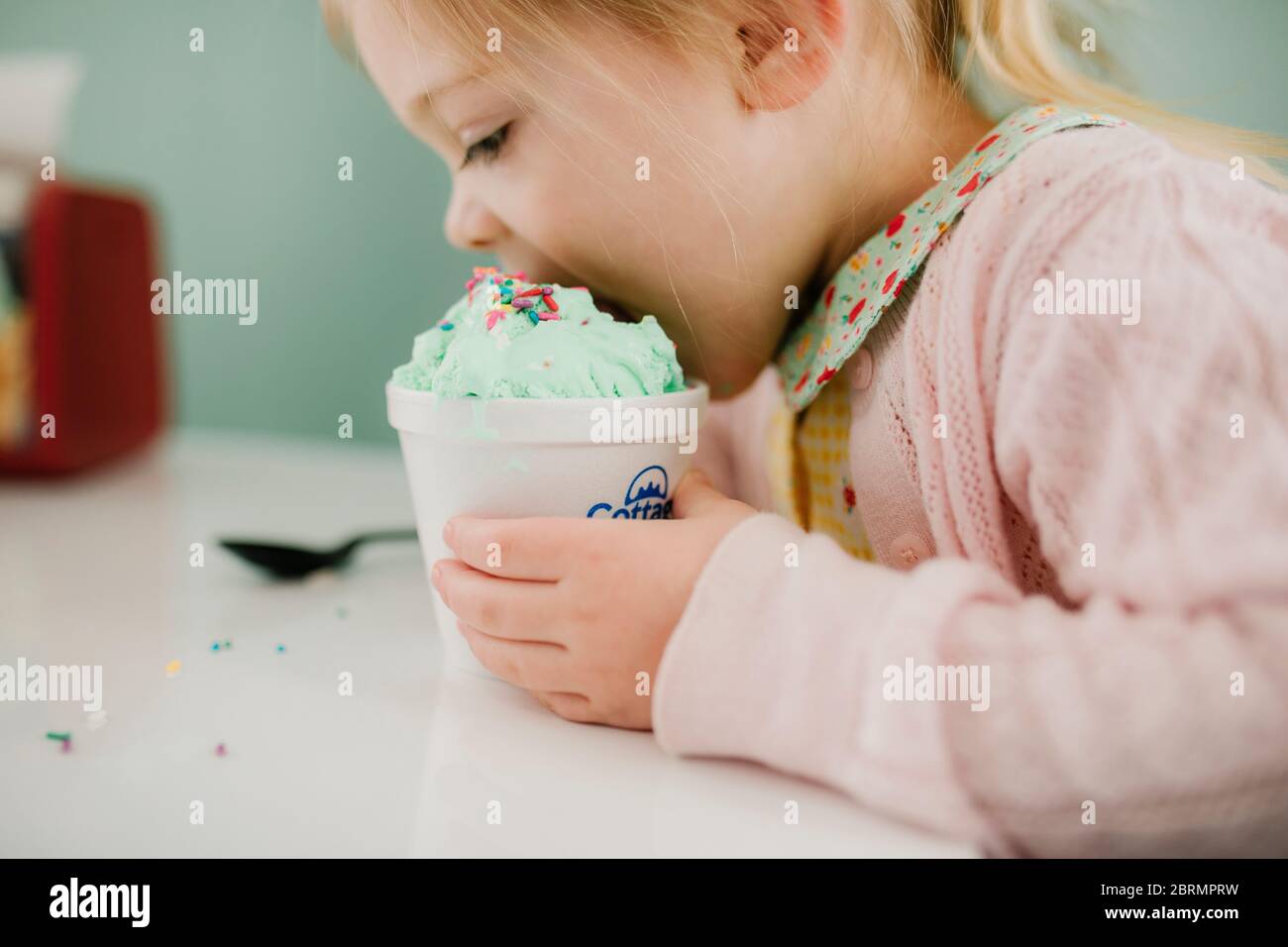 Girl taking a big bite of her green ice cream Stock Photo - Alamy