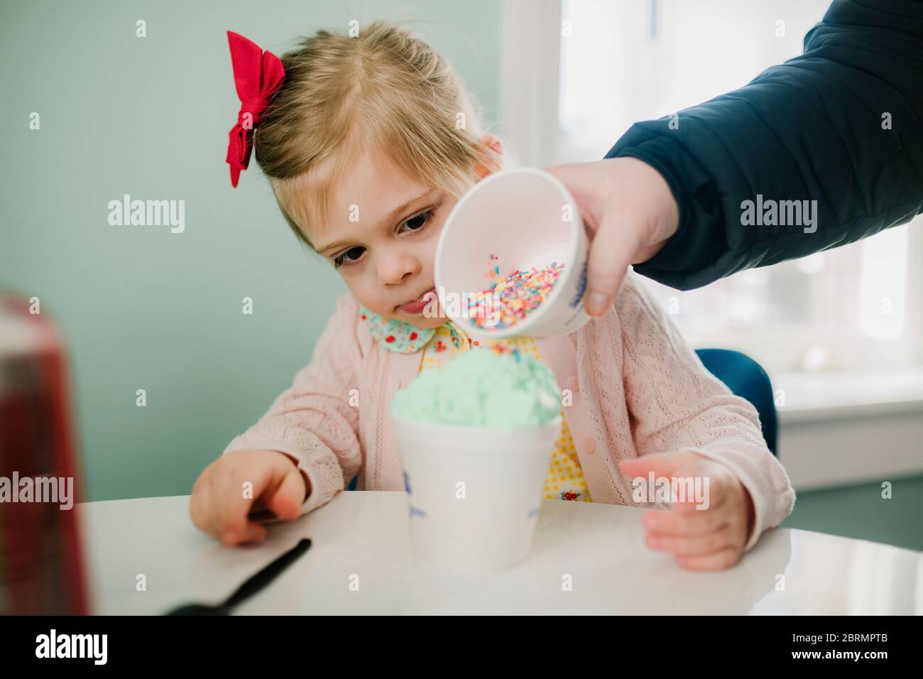Mom pouring sprinkles on girls ice cream Stock Photo - Alamy
