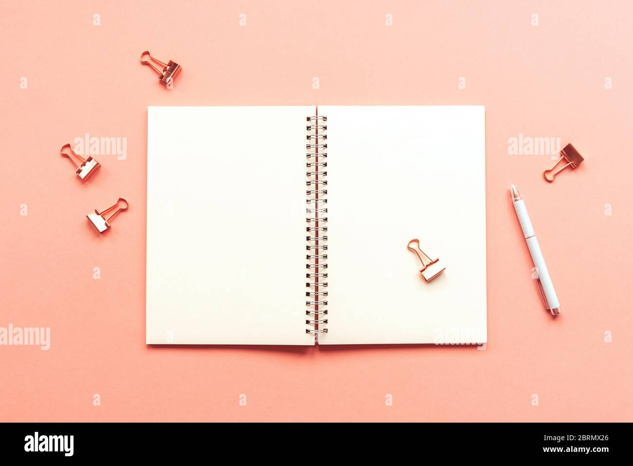 Blank spiral notepad mockup on a coral pink pastel background with pen ...