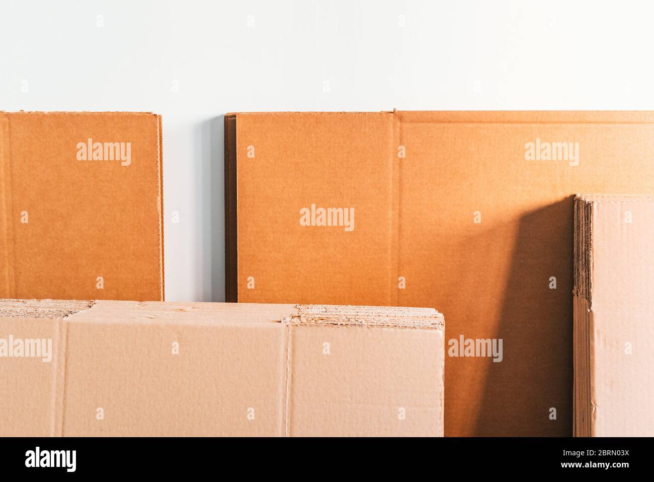 Cardboards stacked on a white wall ready to form boxes to transport ...