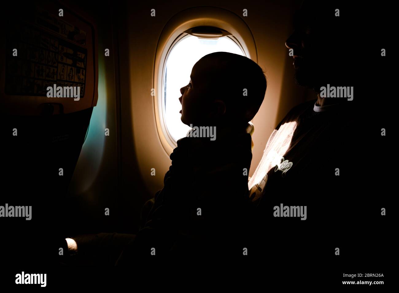 Baby sitting on his father next to the plane's window on a trip Stock ...