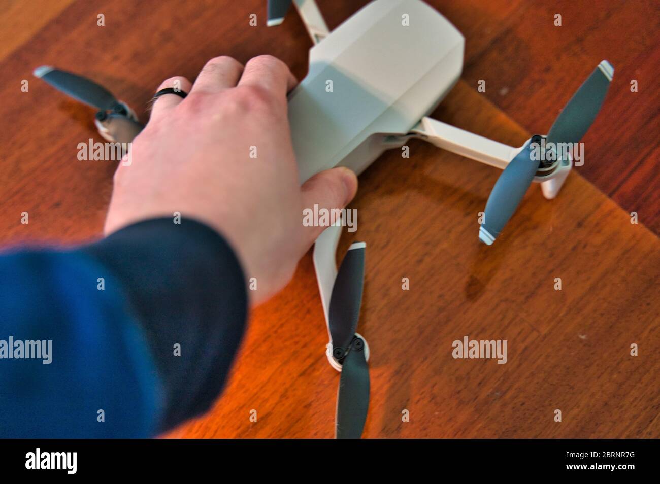 Hand holding drone with wooden deck visible in background. White man's ...