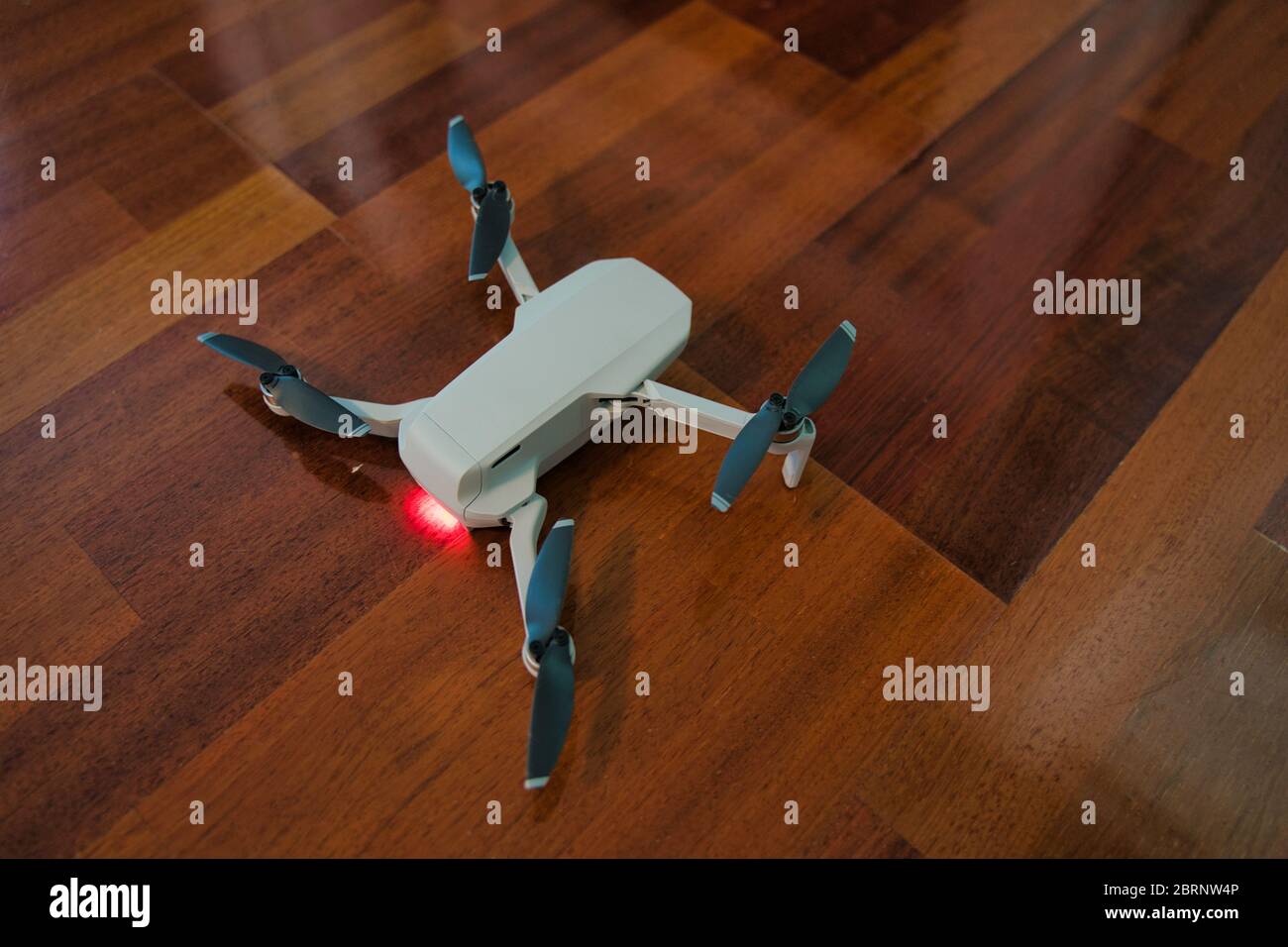 Drone sitting on wooden floor with light on indicating dead battery ...