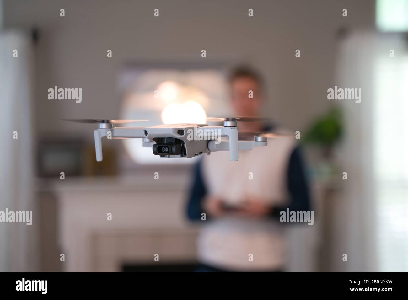 Drone flying indoors with pilot visible in background. Amateur drone ...