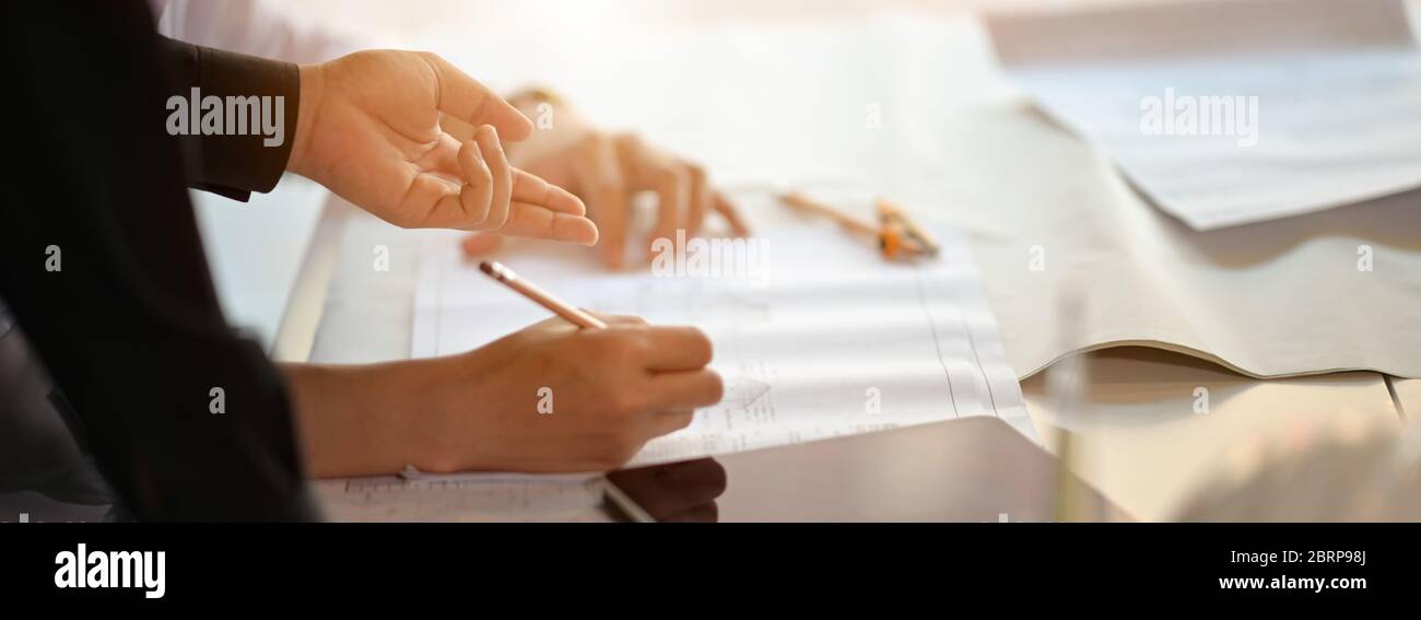 Side view of engineer man hand drawing on blueprint and briefing with ...