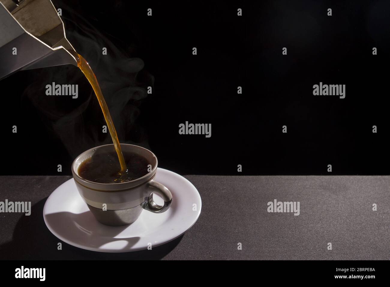 hand serving or pouring hot coffee into a cup in black background Stock ...