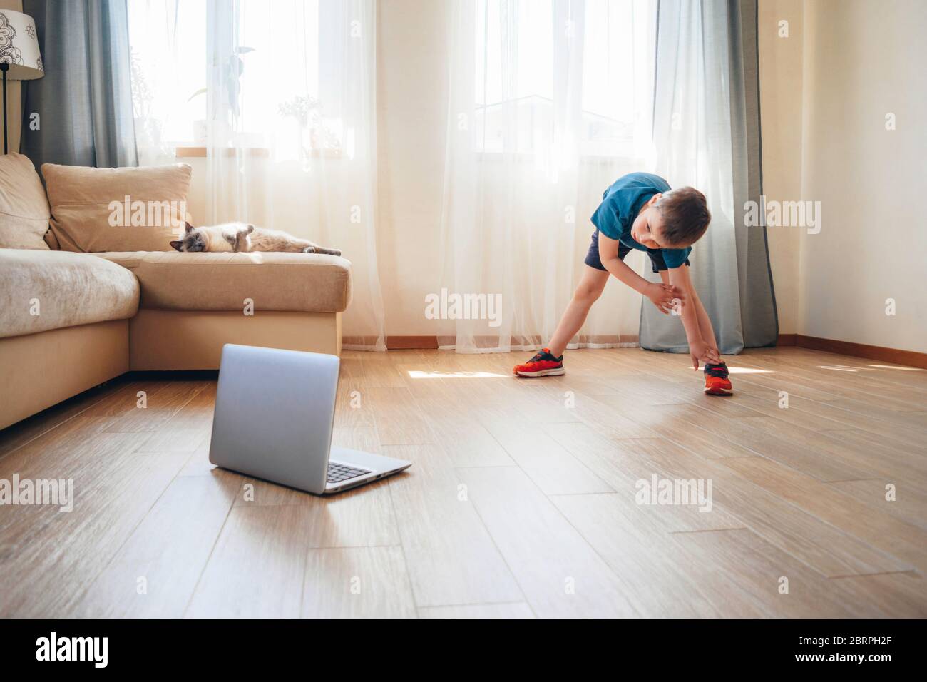 The boy doing physical exercises, watching video lesson online in front ...