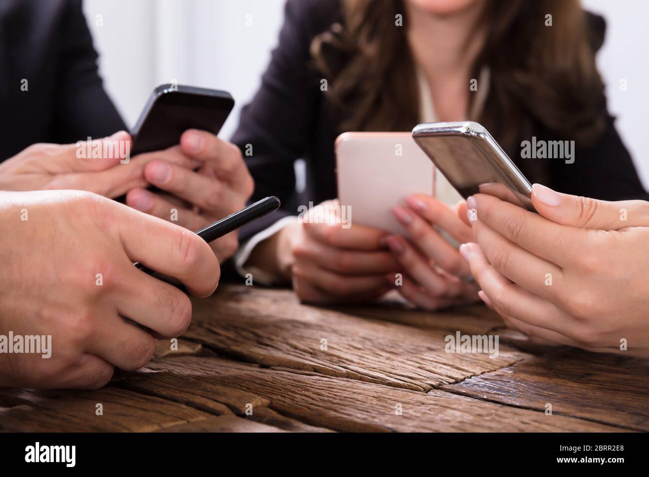 Elevated View Of Businesspeople Using Mobile Phone Over Wooden Desk ...