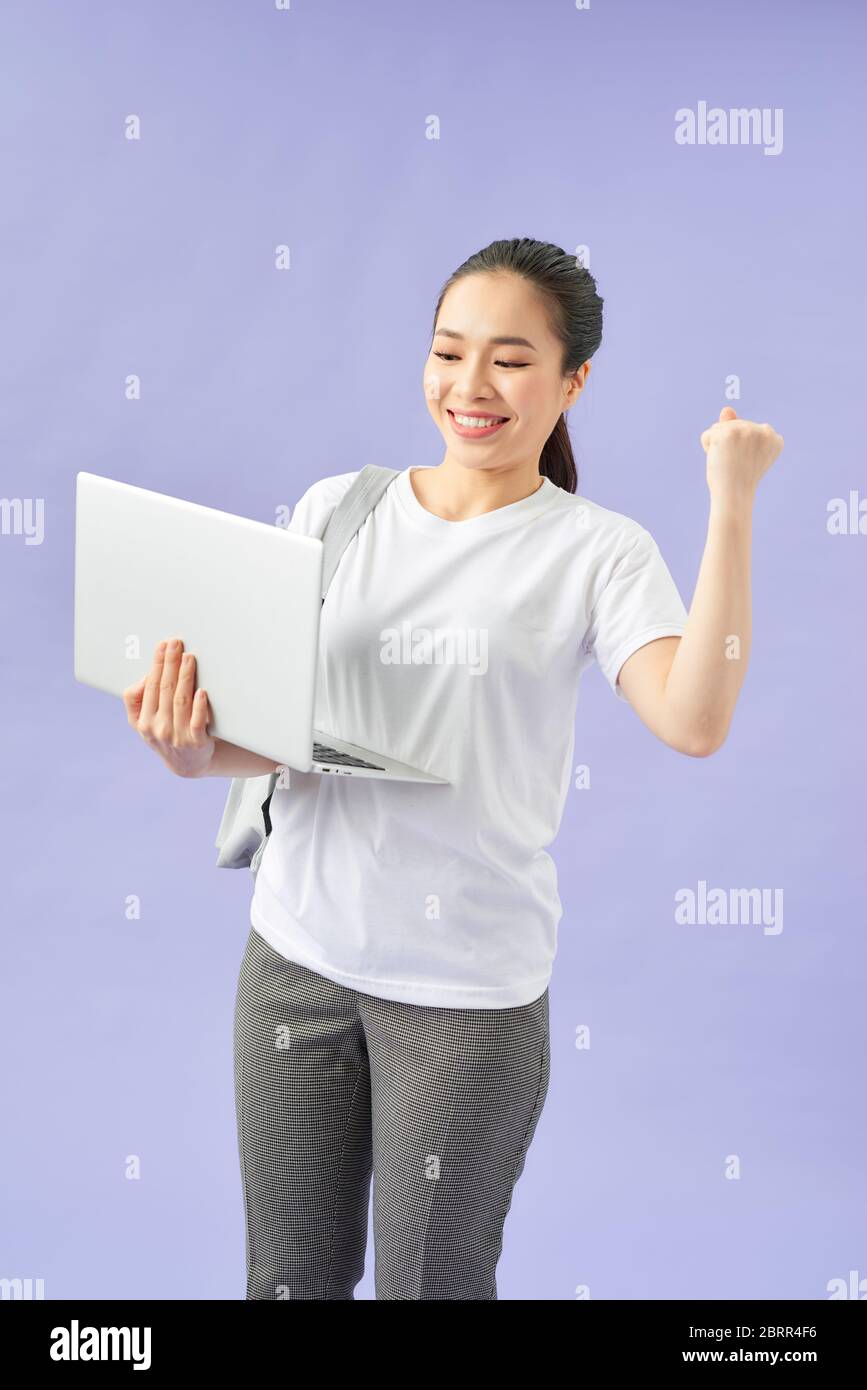 Cheerful female student holding laptop and looking at camera isolated ...