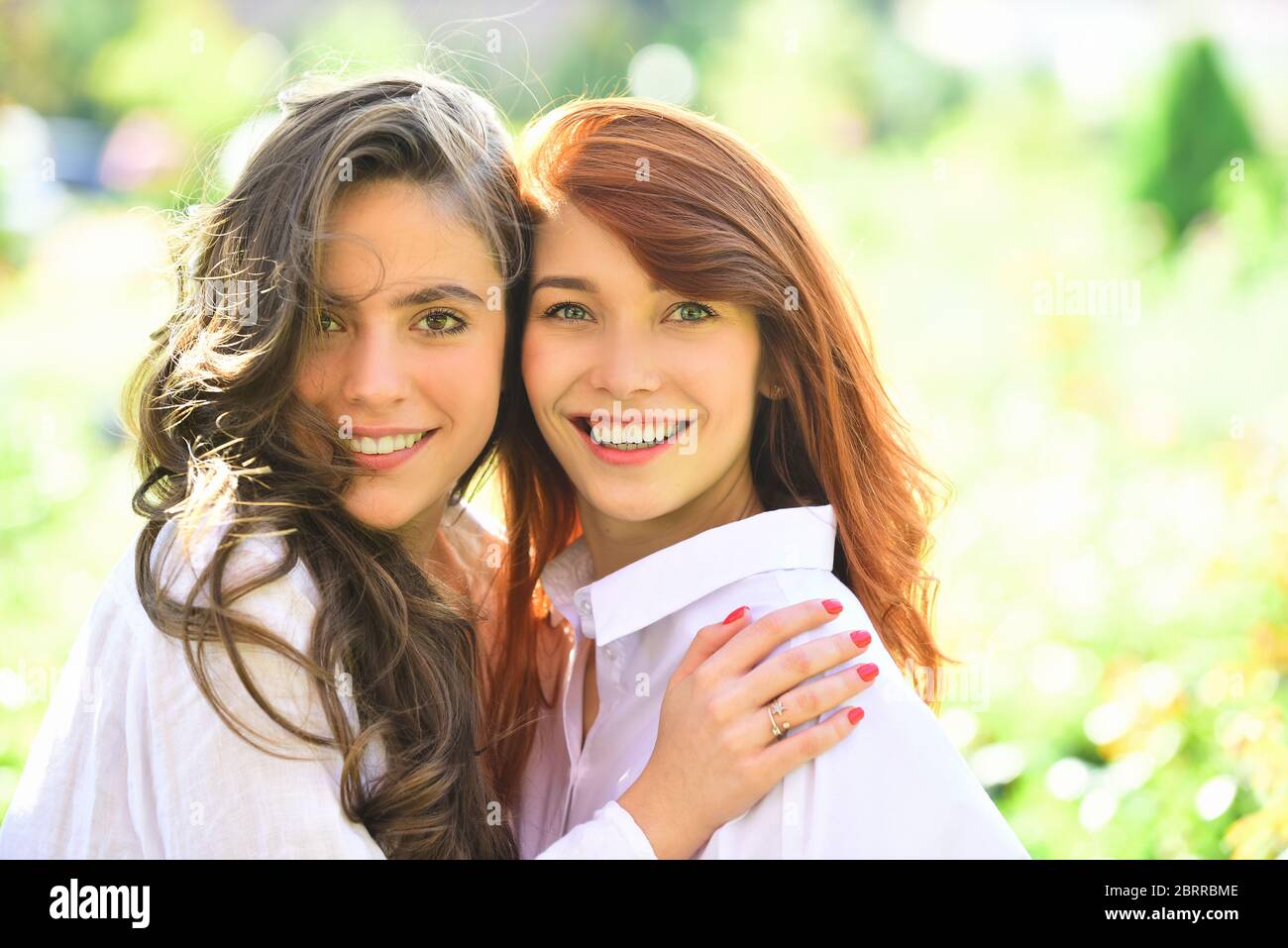 Girl friends laughing and hugging outdoors. Two women are hugging on ...
