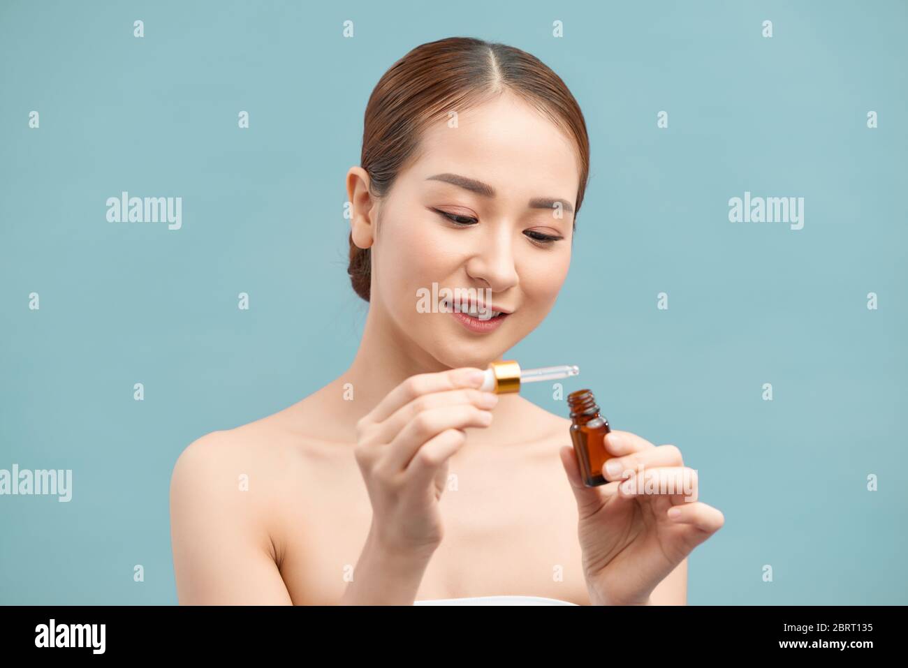 Beautiful model applying a cosmetic skin serum treatment on violet ...