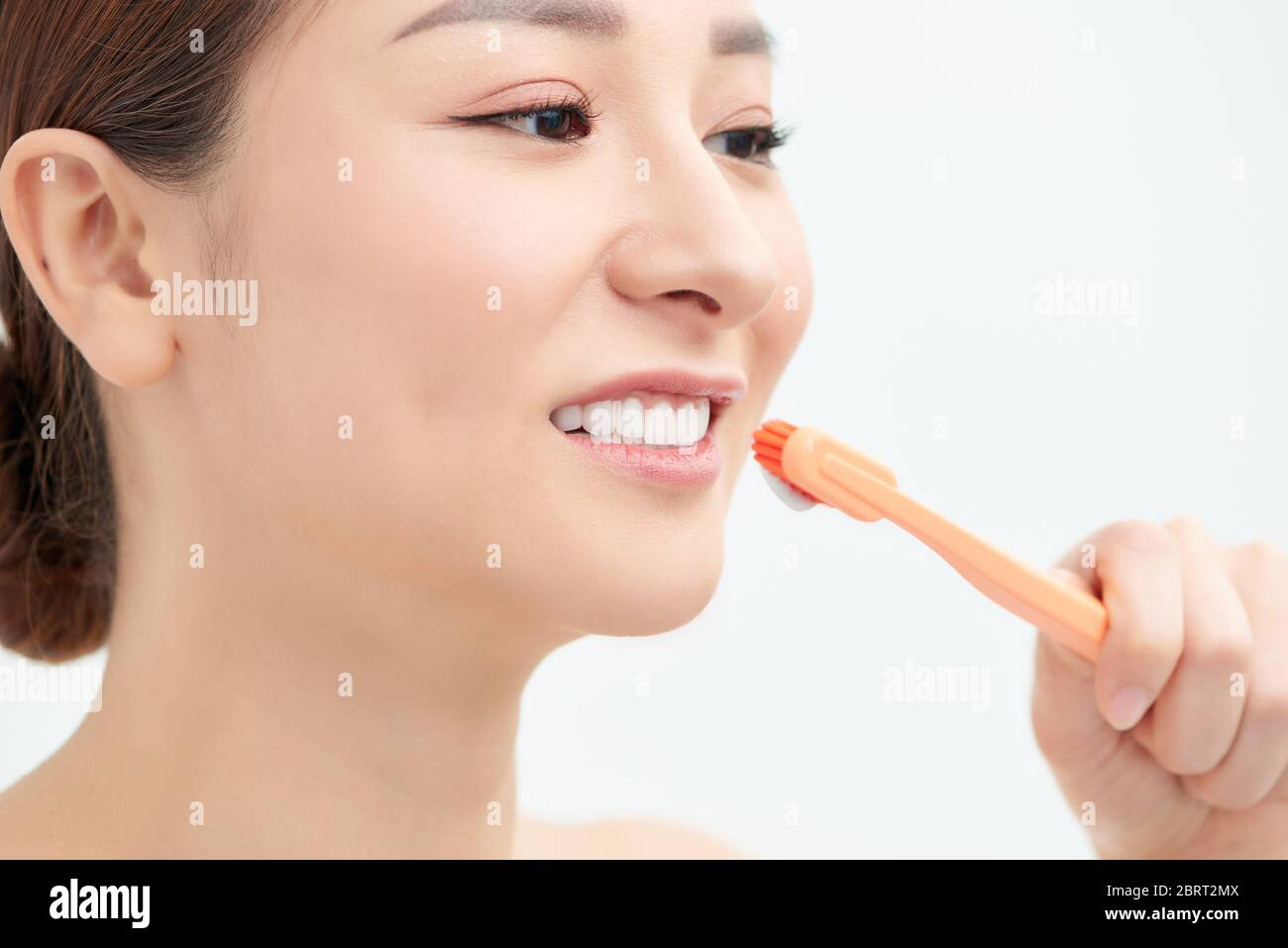 Studio portrait of a beautiful young woman holding a toothbrush with ...