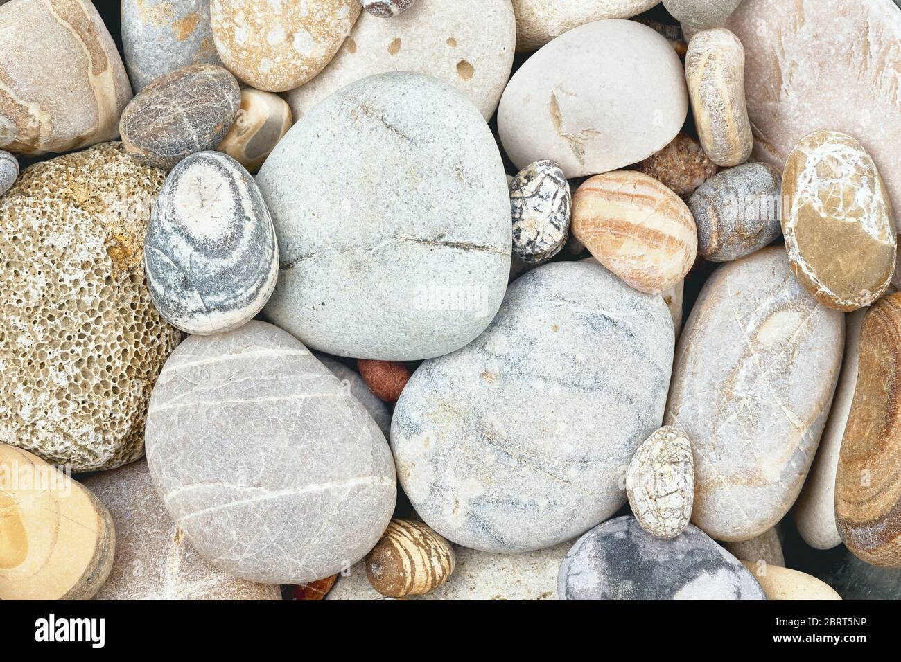 Mix of rounded multicolor textured stones on sea beach . Close up coast ...