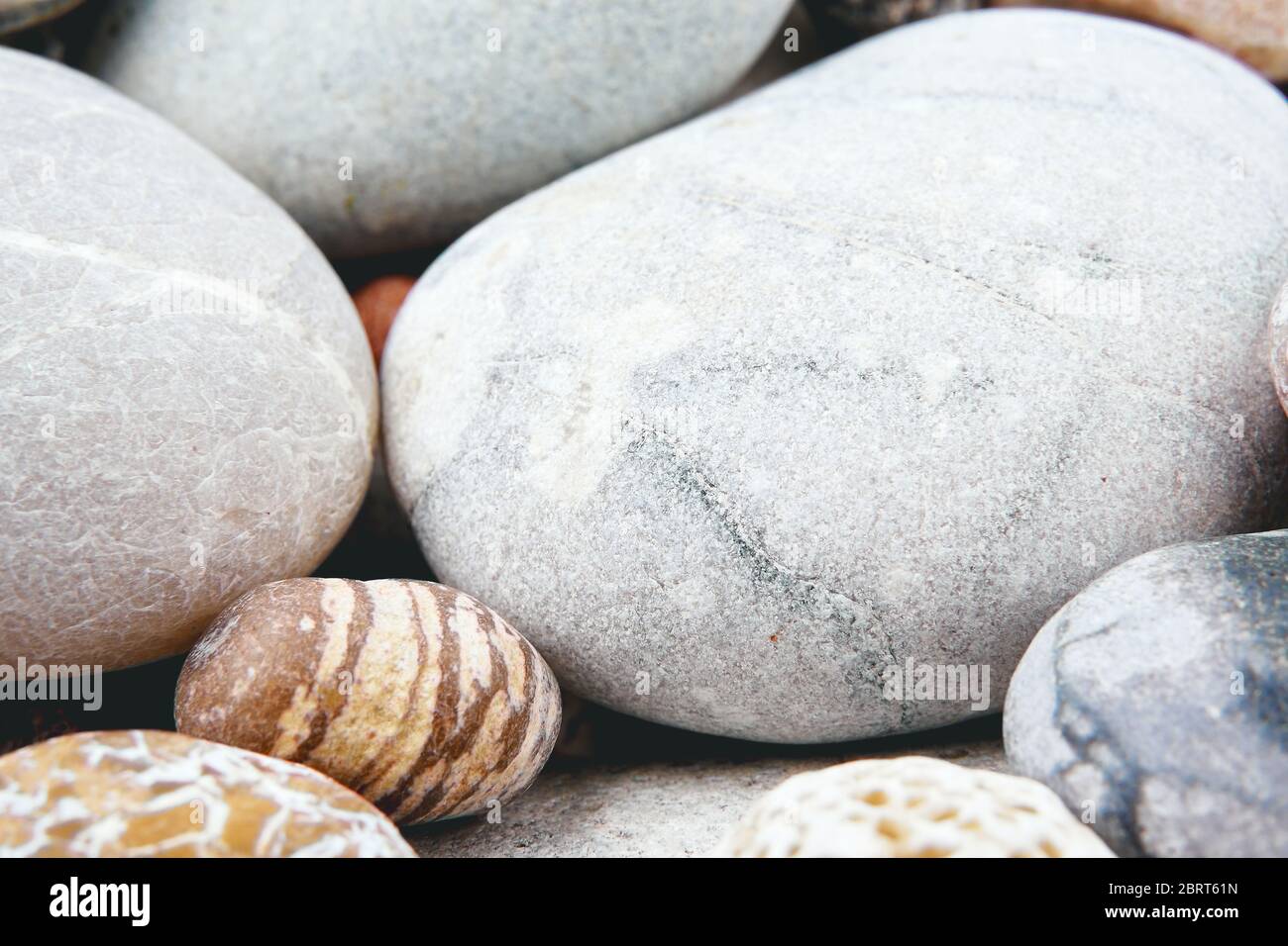 Mix of rounded multicolor textured stones on sea beach . Close up coast ...