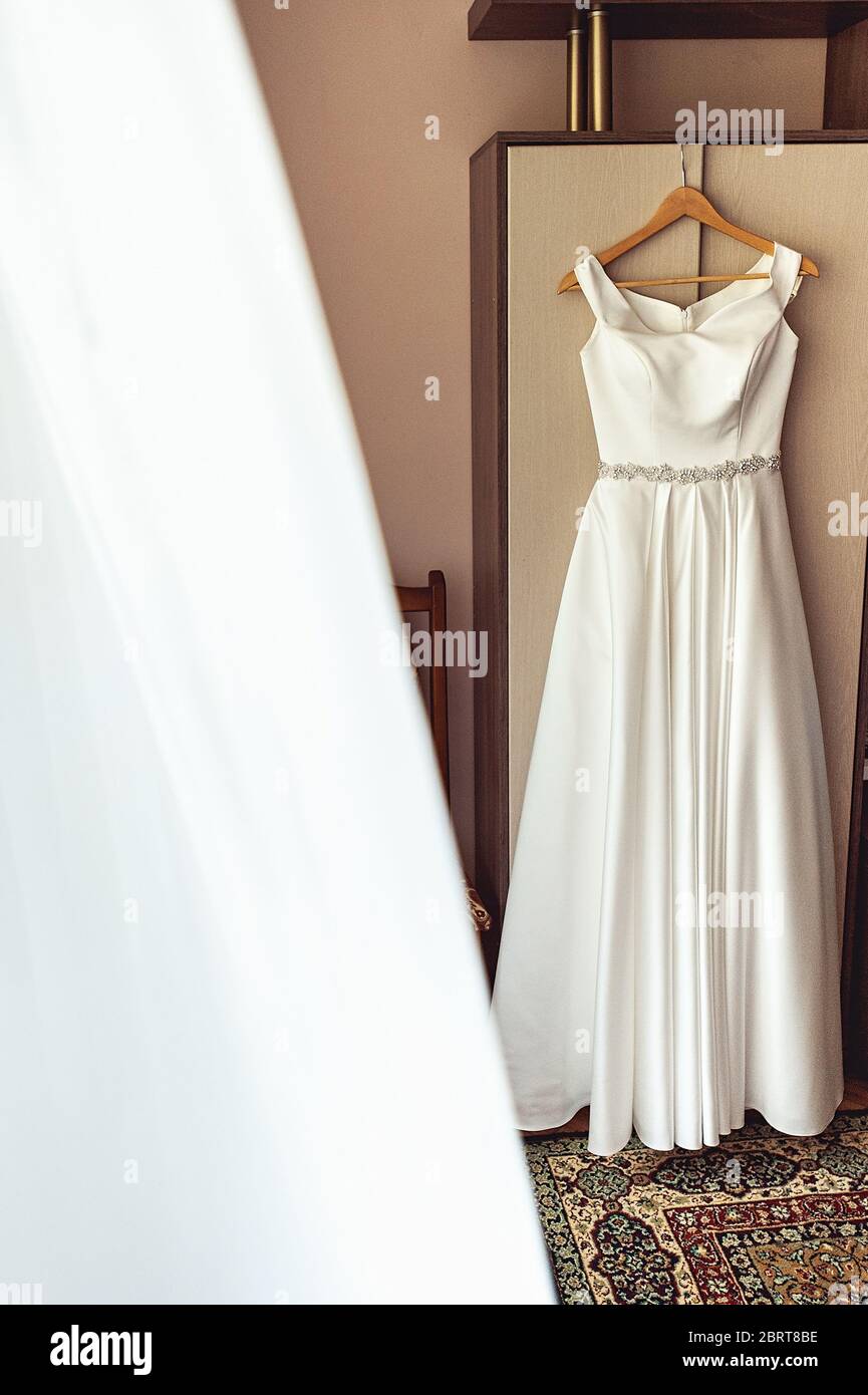 Simple white wedding dress on the rack at the wardrobe Stock Photo - Alamy