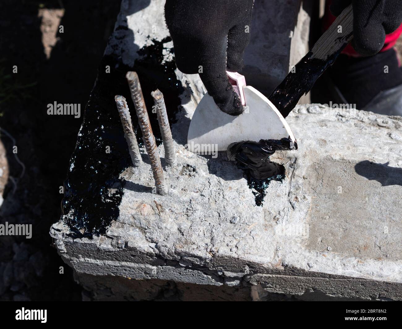Woman hand with a brush covers the strip foundation with bituminous ...