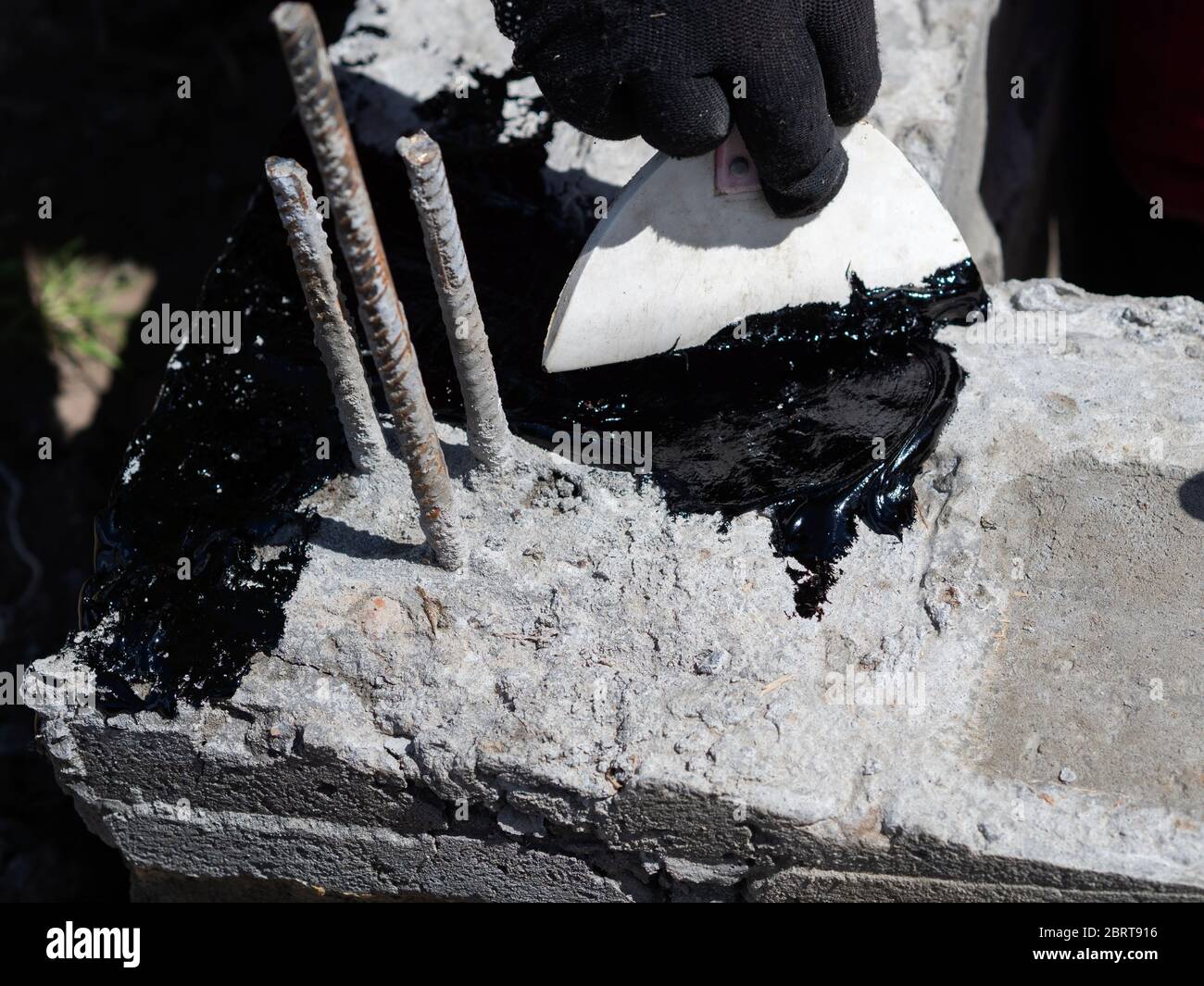 Woman hand with a brush covers the strip foundation with bituminous ...