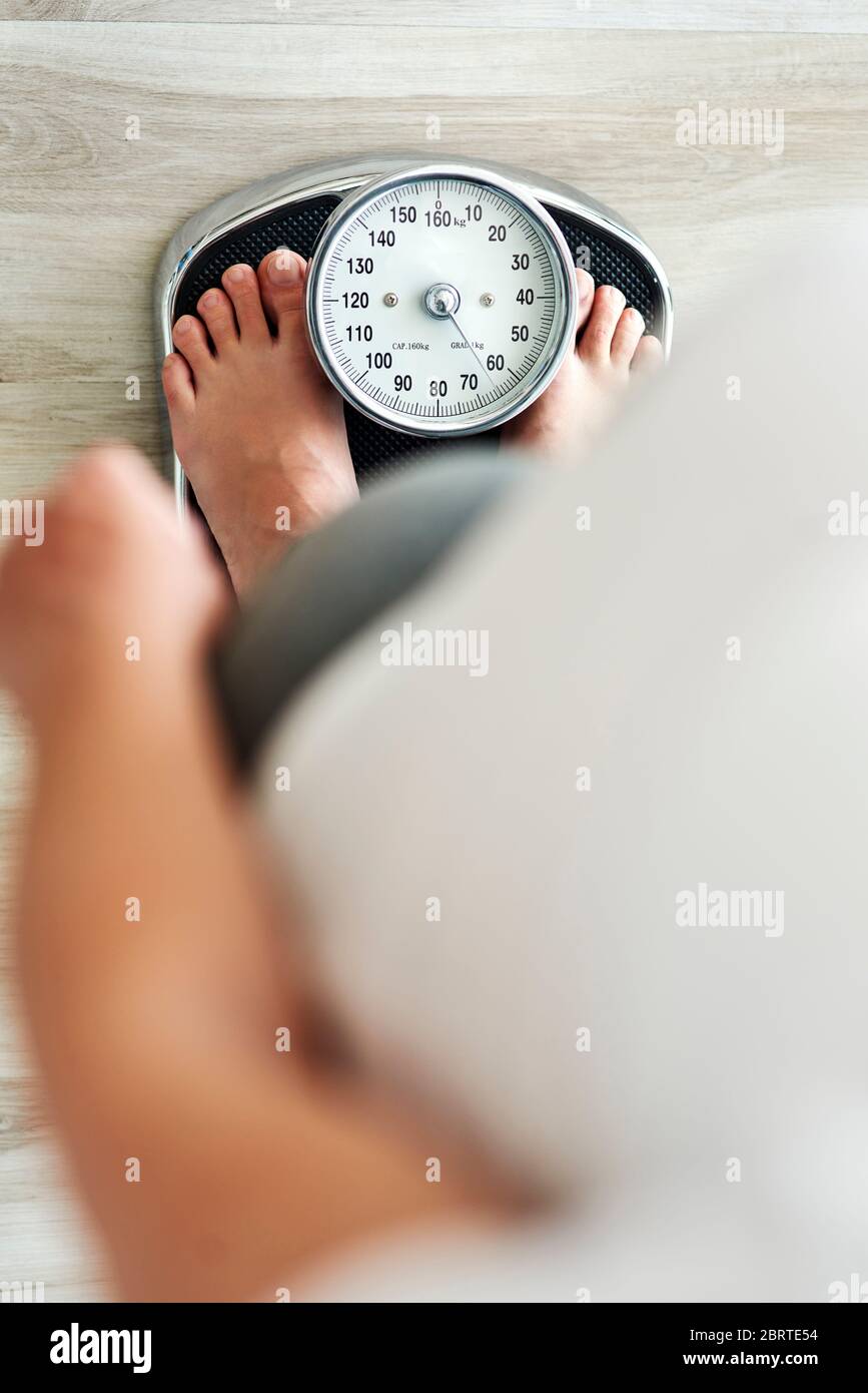 Vertical image of woman standing on a bathroom scale Stock Photo - Alamy
