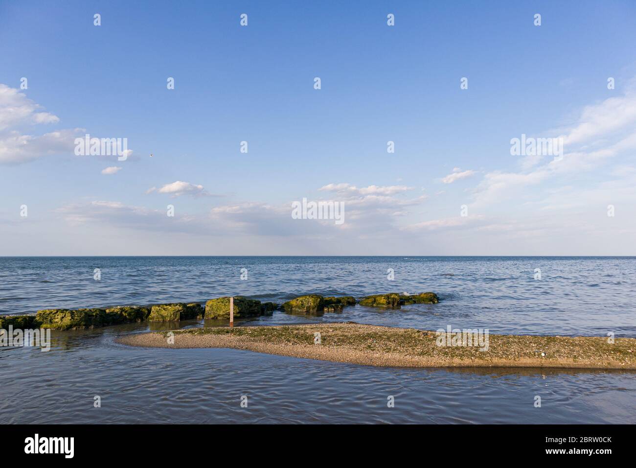 A small sand band leading to a natural breakwater. With blue, clean sky ...