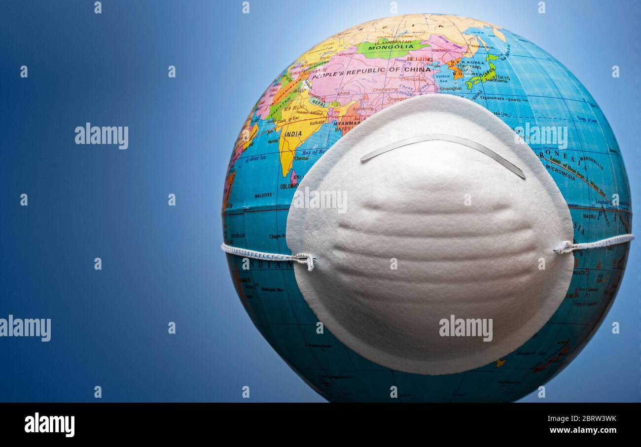Face mask around a world globe in side view over a grey background with ...