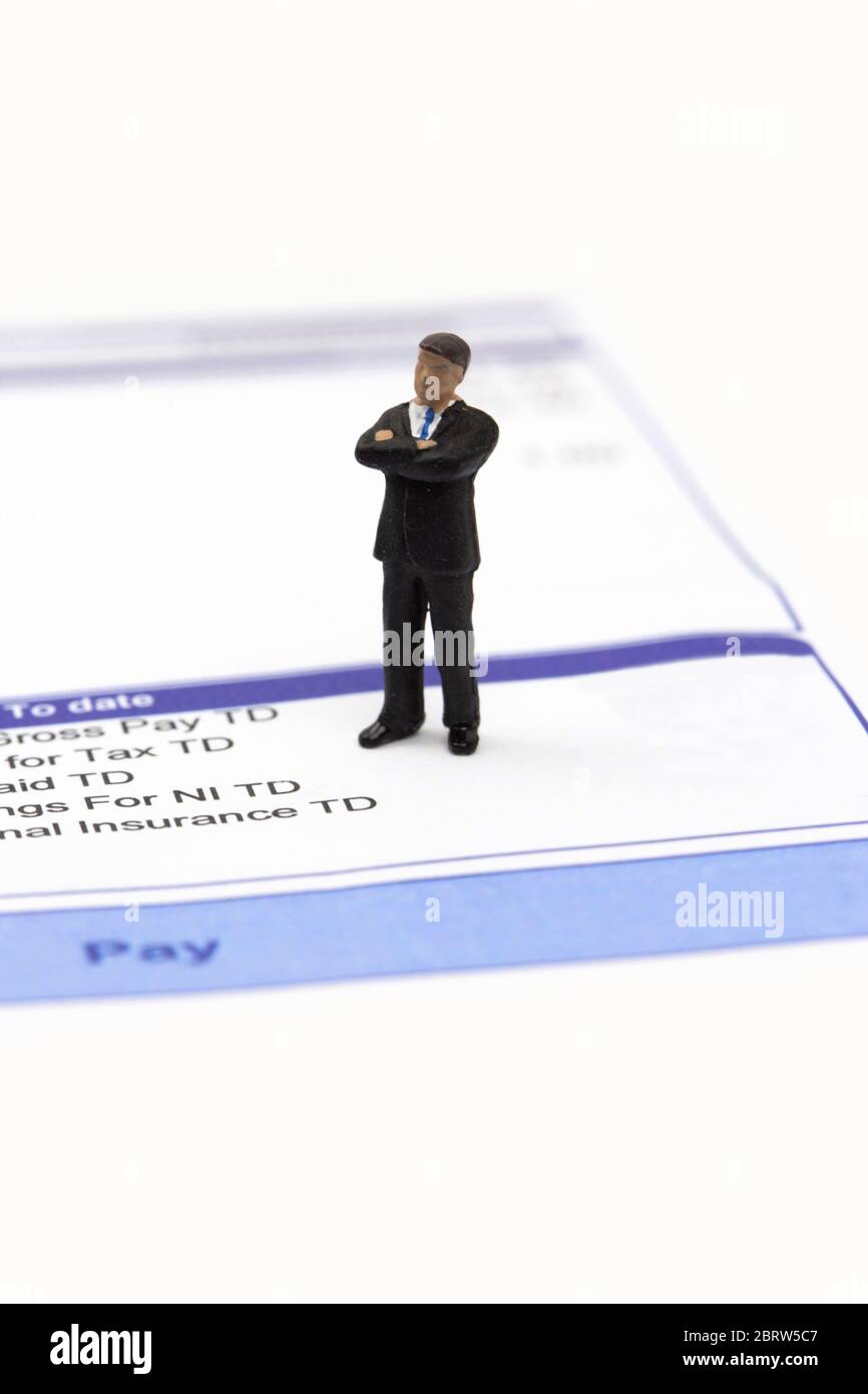 Miniature scale model businessman standing on a wage pay slip showing ...