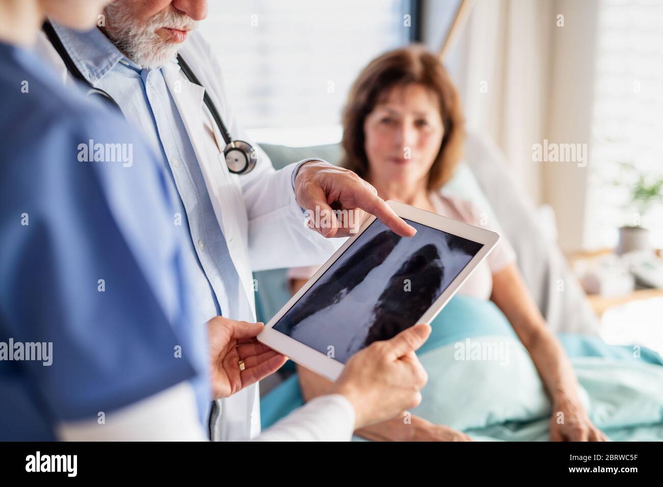 Senior male doctor examining a woman patient in hospital, checking X ...