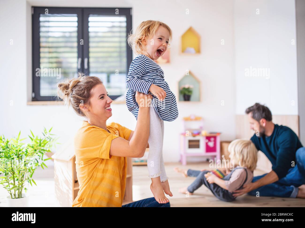 Young family with two small children indoors in bedroom having fun ...