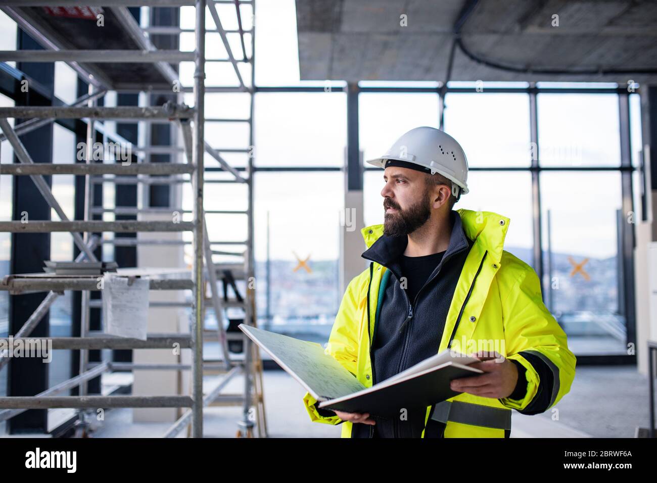 Man engineer standing on construction site, holding blueprints Stock ...