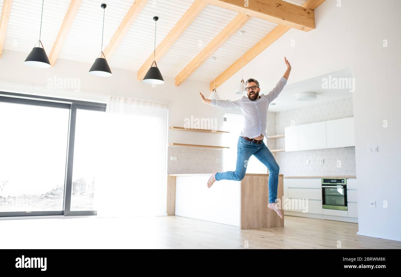 Cheerful mature man moving in new unfurnished house, jumping Stock ...