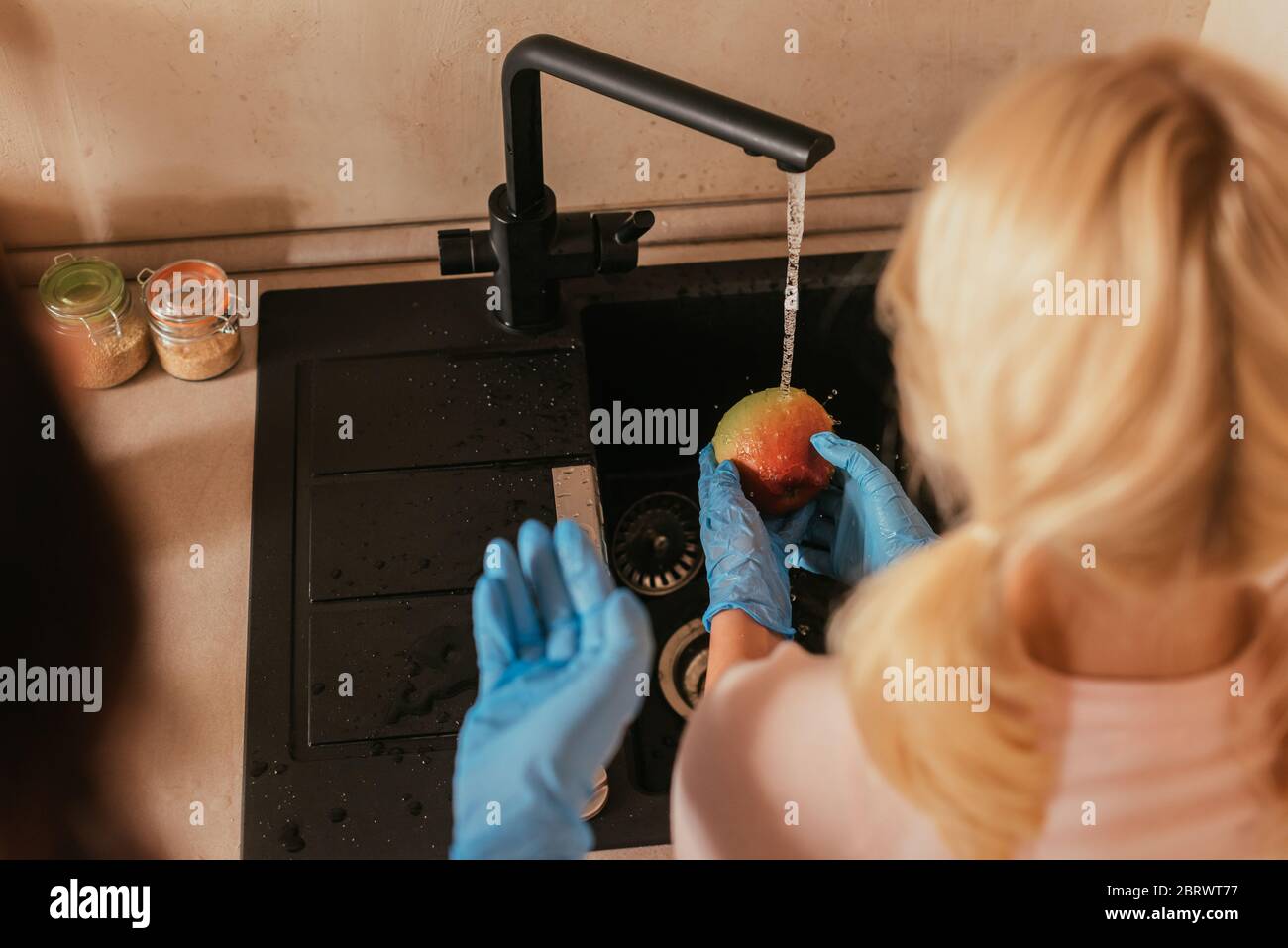 Selective focus of kid in latex gloves washing apple near mother Stock ...