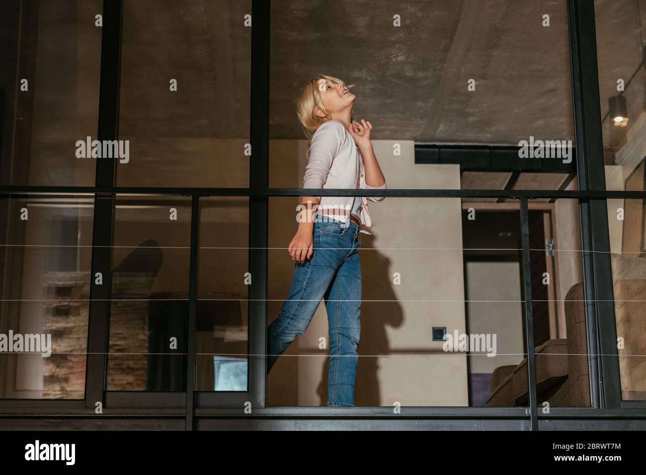 Side view of cheerful child standing near window in living room Stock ...