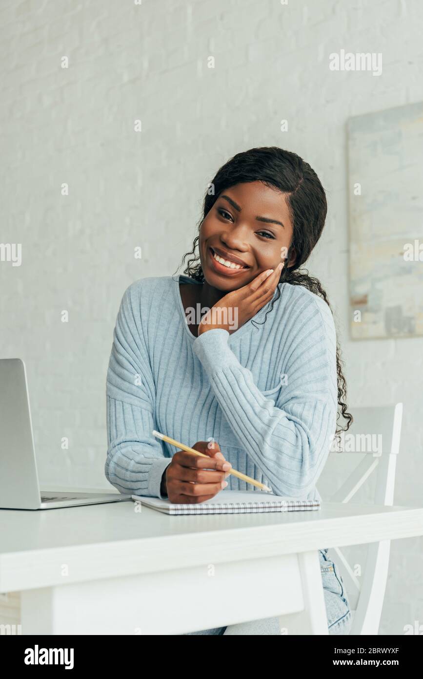 happy african american freelancer smiling at camera while holding ...