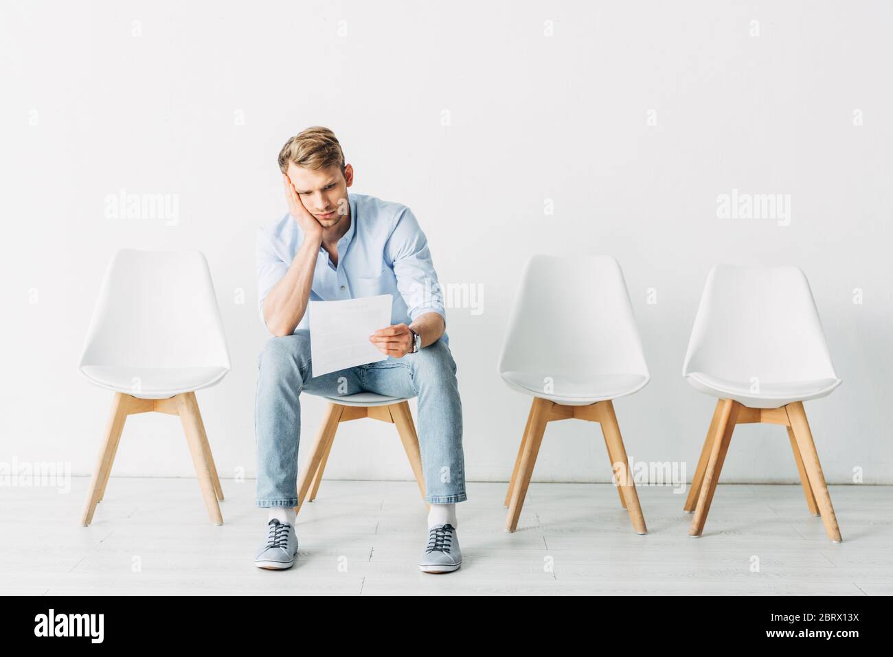 Tired man looking at resume while sitting on chair in office Stock ...