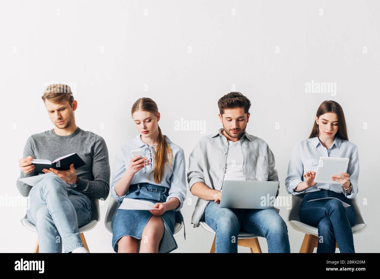 Employees using digital devices while waiting for job interview in ...