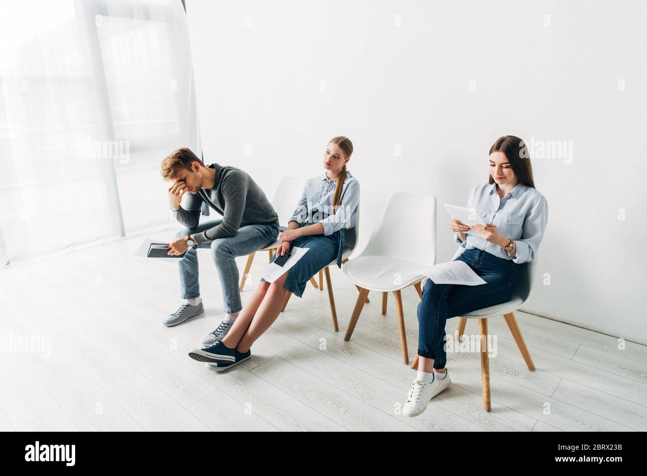 Tired man and women waiting for job interview in office Stock Photo - Alamy