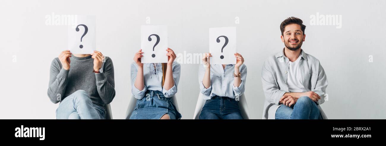 Panoramic shot of smiling man looking at camera near employees holding ...