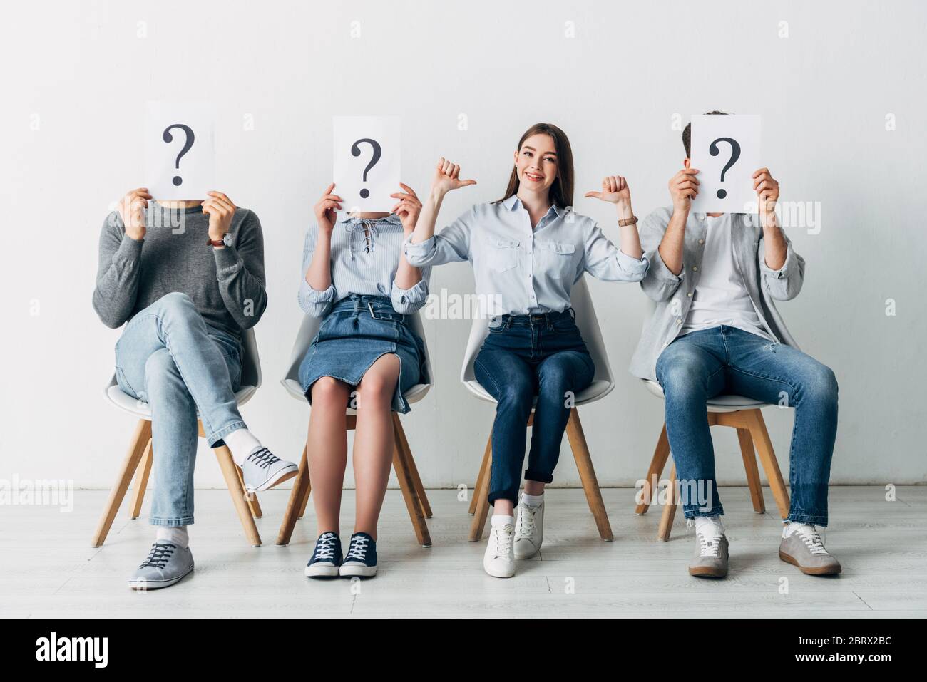 Smiling woman showing thumbs up near employees with question marks on ...