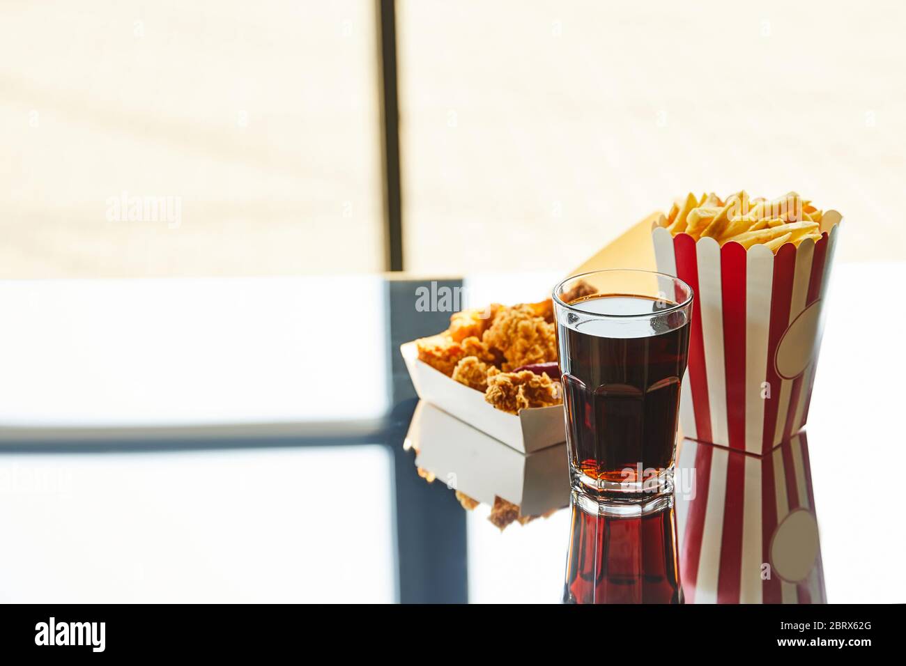 deep fried chicken, french fries and soda in glass on glass table in ...