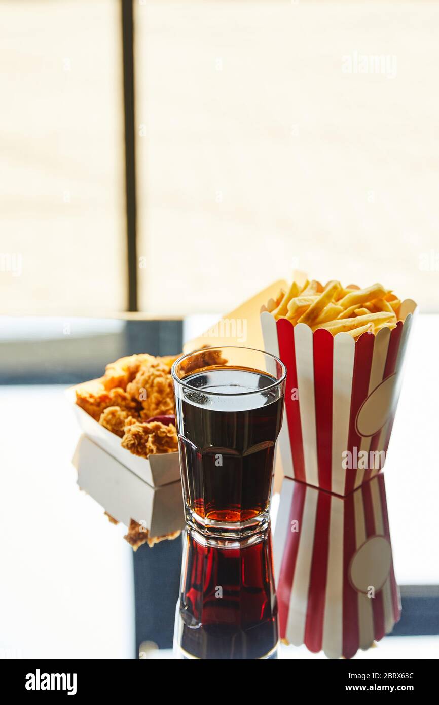 deep fried chicken, french fries and soda in glass on glass table in ...