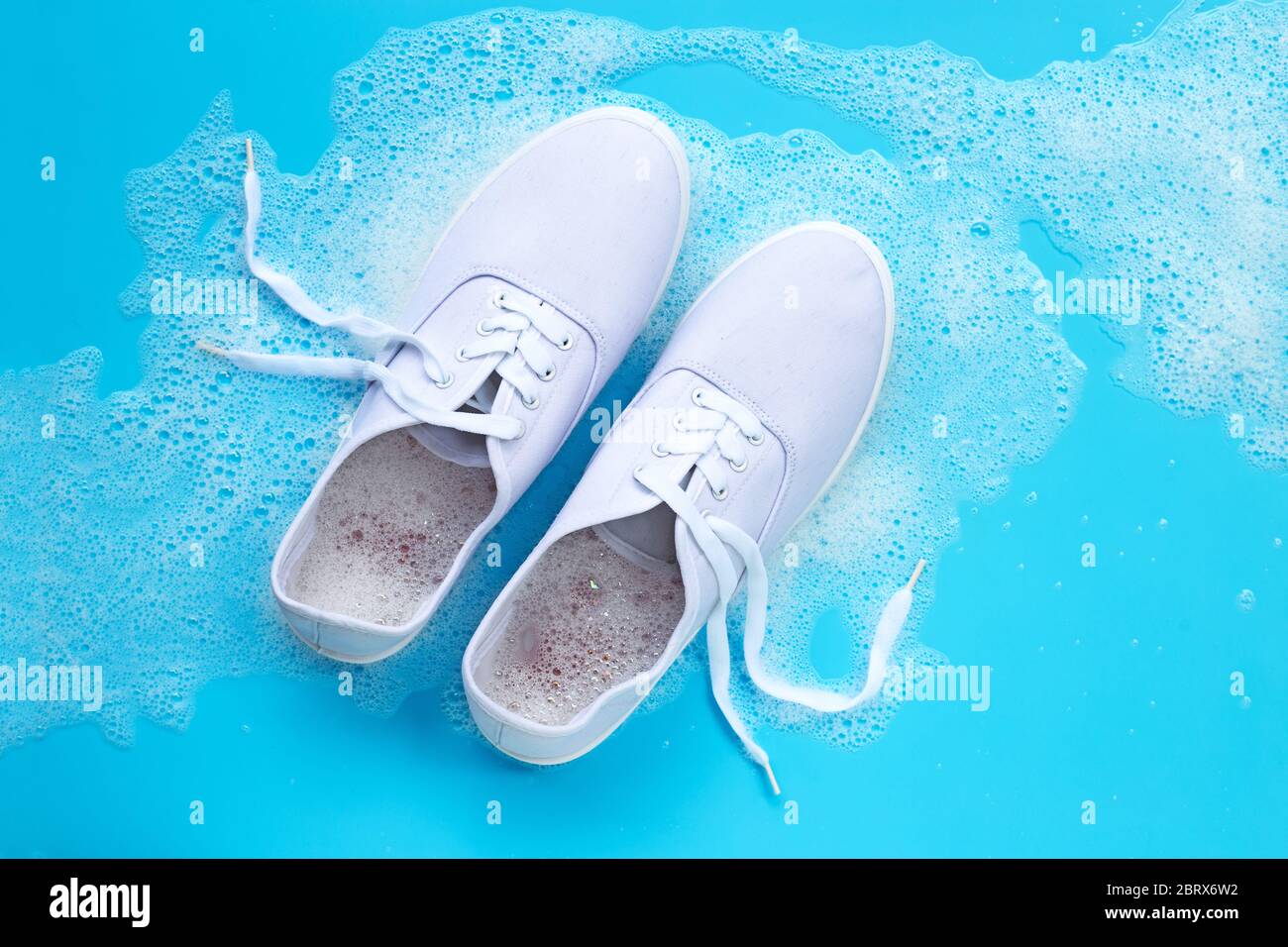 Sneakers with foam of powder detergent water dissolution on blue ...