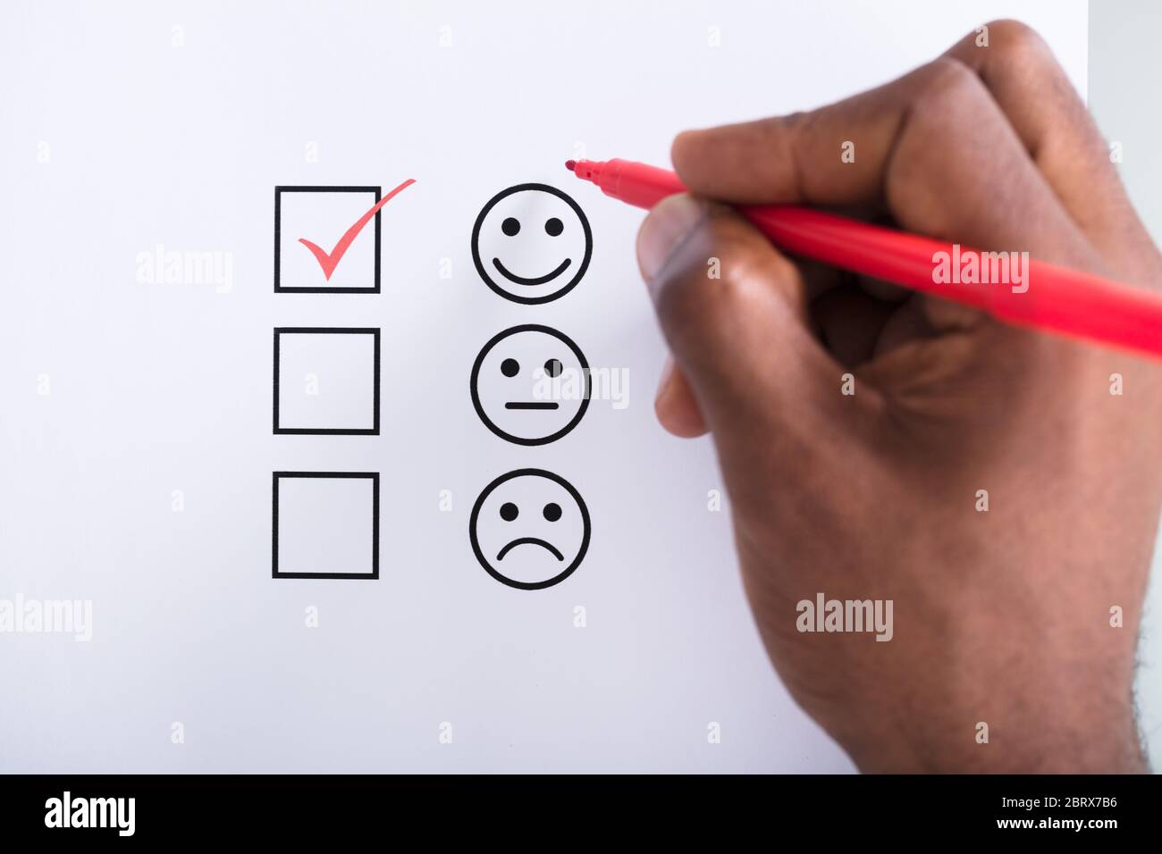 Person's Hand Ticking Off Checked Box Near The Smile Emoji With Red Pen ...
