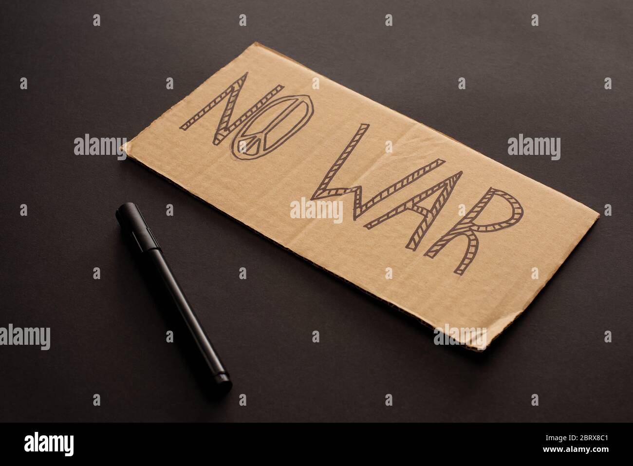 cardboard placard with no war lettering and peace sign near marker on ...