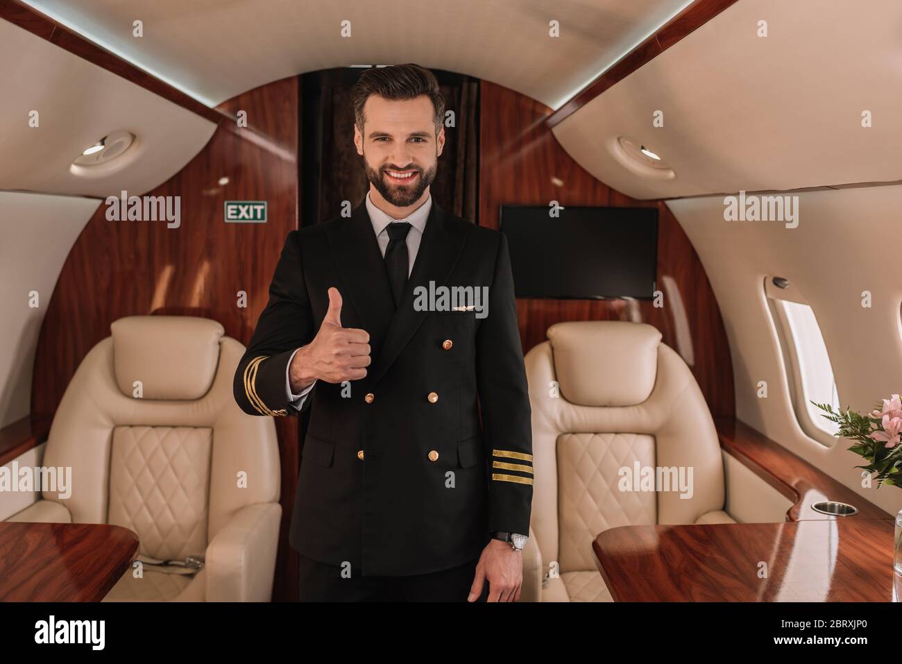 handsome pilot of private jet showing thumb up while smiling at camera ...